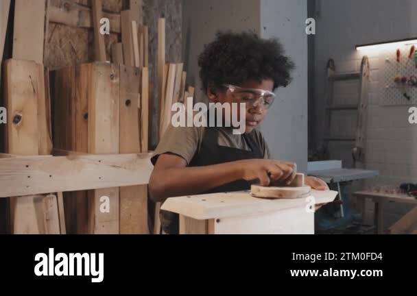 African American pre-teen boy making surface of birdhouse flat when ...