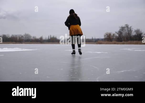 Lady shot in figure skates sliding on ice surface at nature. Woman ...