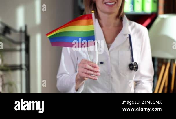 Hands of female doctor with lgbt flag waving in clinic office. Medical ...