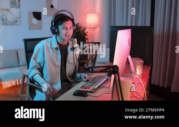 Medium shot of gen z Asian gamer speaking in mic while recording and ...