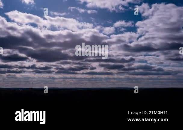 Timelapse of cumulus clouds moving in the sky with sun over the horizon ...