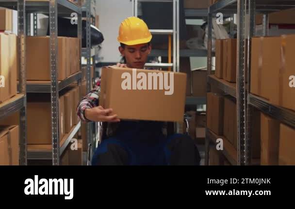 Man in wheelchair working in storage room with goods, employee with ...