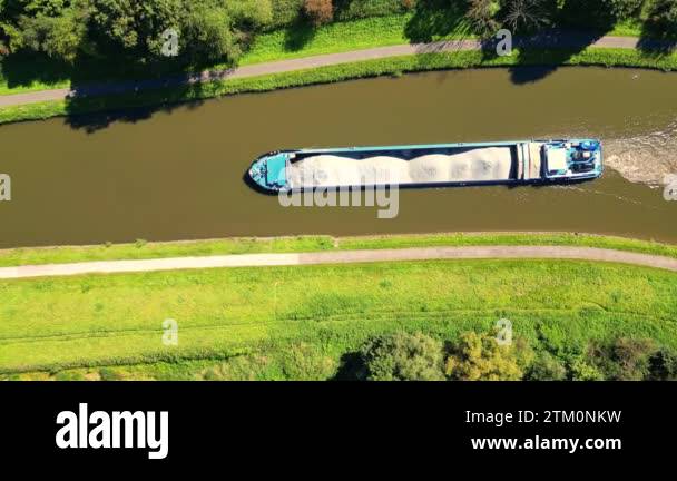 Suspended above, the camera captures a unique narrative: a hefty cargo ship, its deck filled ...