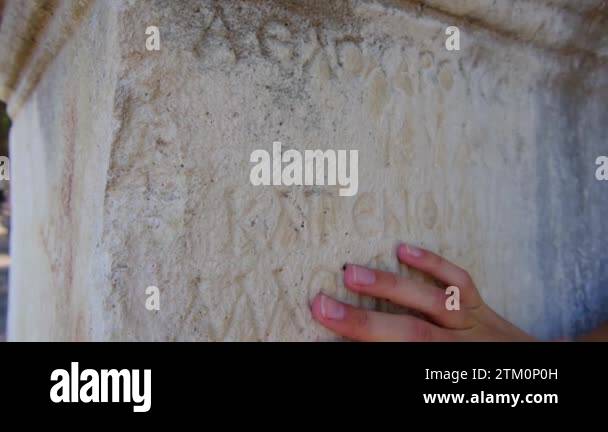 female hand traces inscriptions on stone ruins, mediterrenean old city ...