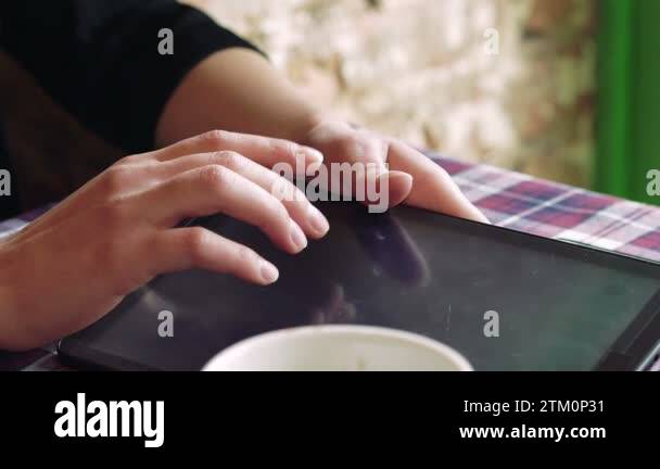 Woman hands touching tablets display at a table with a cup of coffee ...