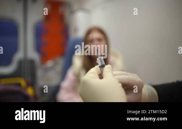 A paramedic in an ambulance prepares to give an injection to a patient ...