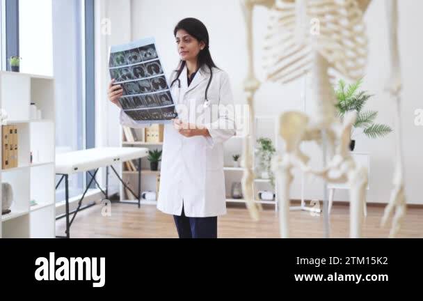 Confident indian doctor holding MRI scans of human brain in consulting ...