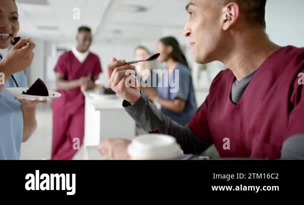 Diverse male and female doctors eating birthday cake at reception desk ...