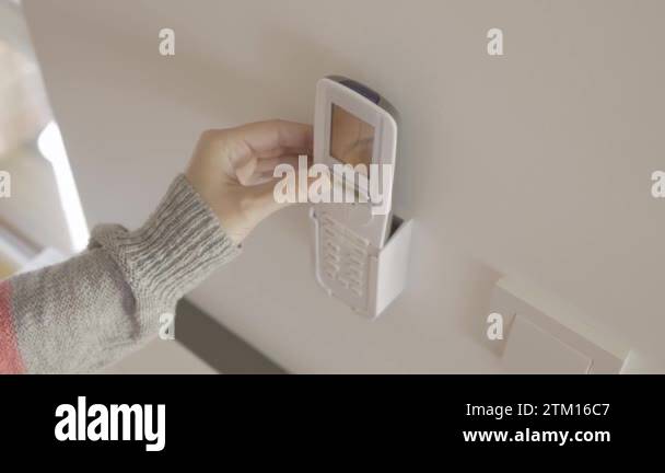 The woman presses the power button on the remote control of the air ...