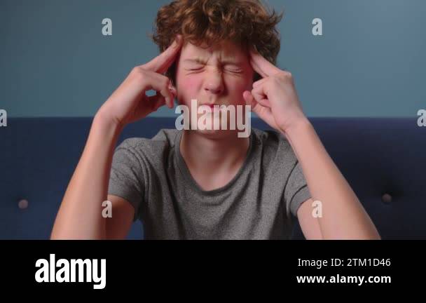 Young depressive boy is sitting and crying about the pain with his head ...