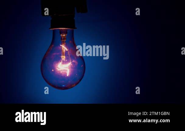 Light bulb lights up and goes out on a blue background in the dark ...