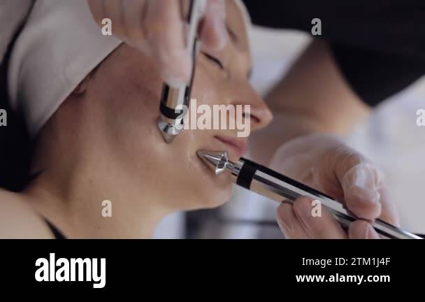 Beautician makes woman micro currents face cheek therapy. Girl skin ...