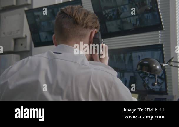 Security operator talks by landline phone in observation room. Security ...