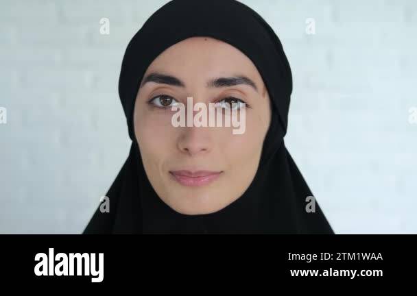 Close-up of the face of a Muslim woman in a black hijab against a white ...