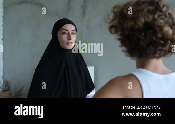 Two women are debating about religion. A Muslim woman in a black hijab ...