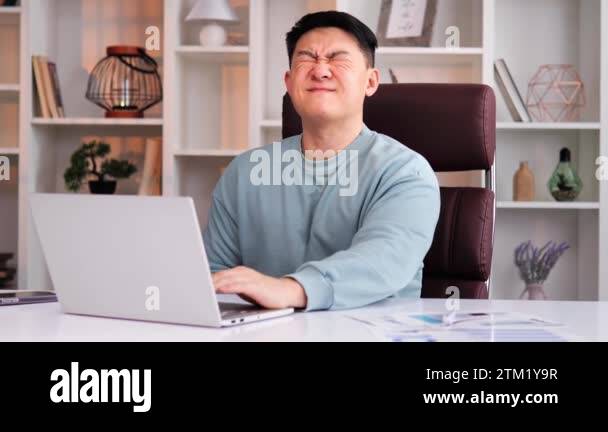 Chinese businessman is hard at work in office, typing away on laptop ...