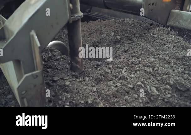 Asphalt unloaded from wheelbarrow. Paver at asphalt pavement works for ...