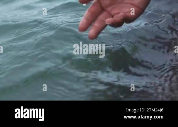 Hands, water and nature with the hand of a woman touching the ocean or sea at the beach. Earth ...