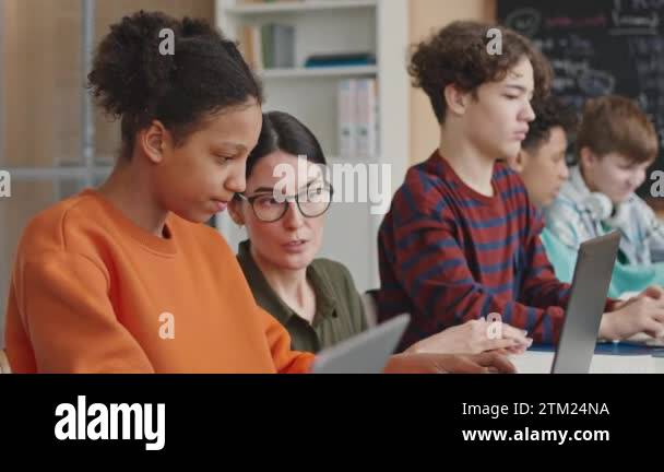 Young Caucasian female teacher helping African American schoolgirl ...