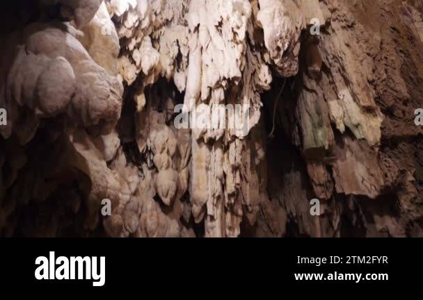 Rocky terrain inside a naturally formed cave with stalactites hanging ...