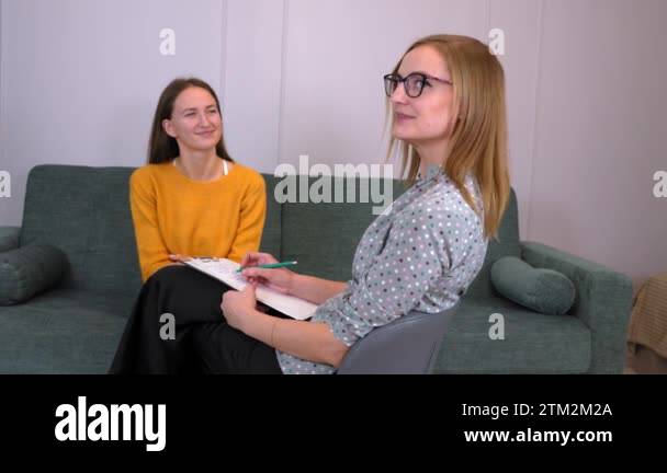 Two girls talking and discussing project. One of them turns to camera ...