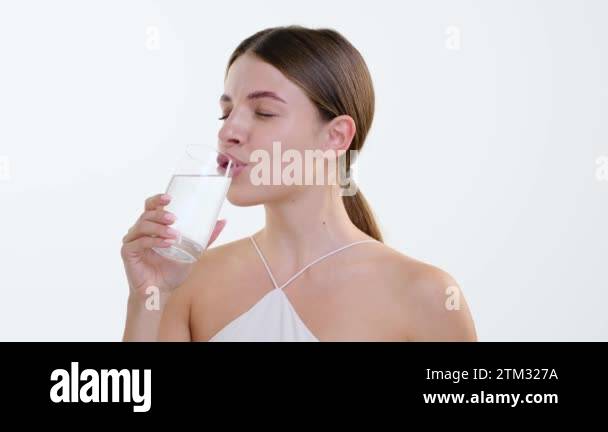 Woman gracefully lifts a glass of water to lips, taking a refreshing ...