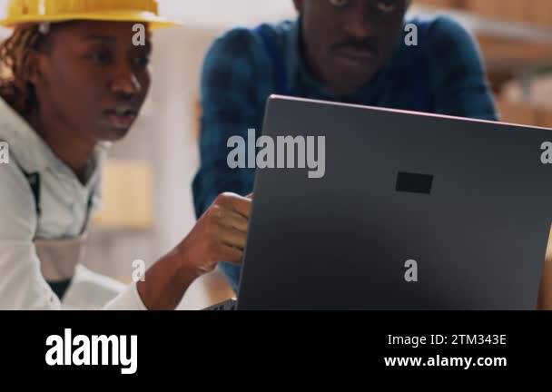 Two young people in overalls working in warehouse, reading products ...