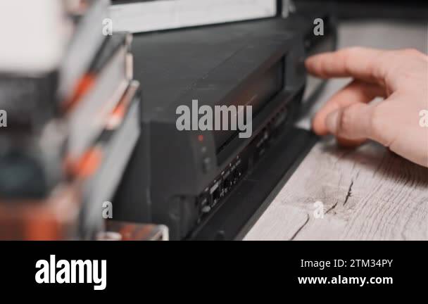 Eject VHS tape cassette from VCR player. Male hand pulls out VHS from a ...
