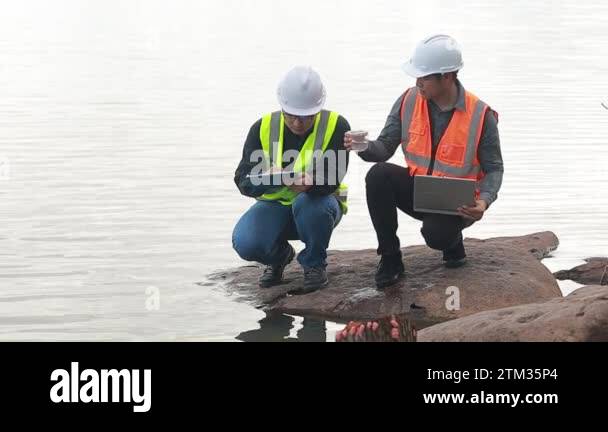 Environmental two engineers work at water source to check for contaminants in water sources and ...