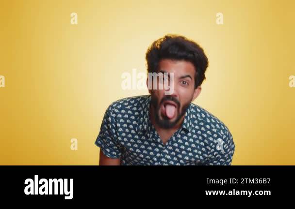 Young indian man showing tongue making childish faces at camera ...