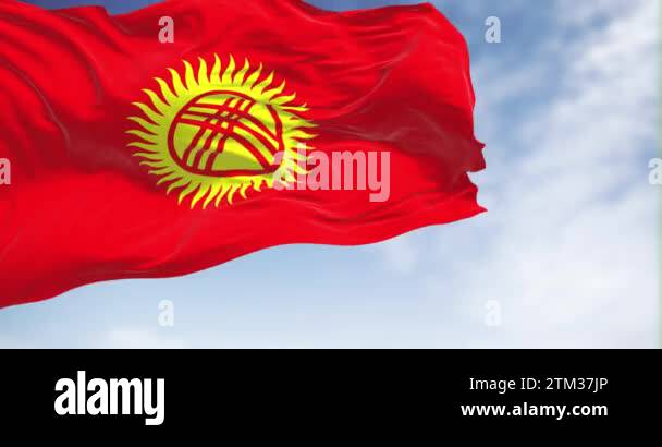 Kyrgyzstan national flag waving on a clear day. Red field, yellow sun ...