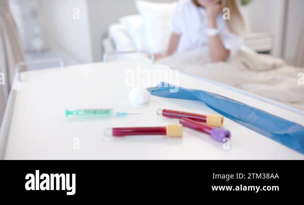 Syringe and blood samples on table, and defocused patient in hospital ...