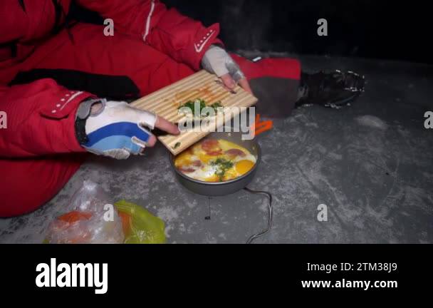 A guy cooks food on gas inside an ice cave. The climber lights the ...