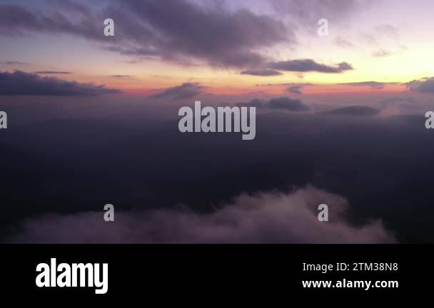 Low key aerial view evening flight over clouds and hills in the ...