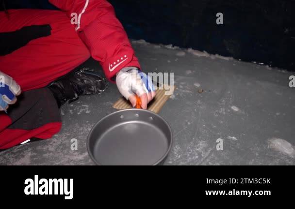A guy cooks food on gas inside an ice cave. The climber lights the ...