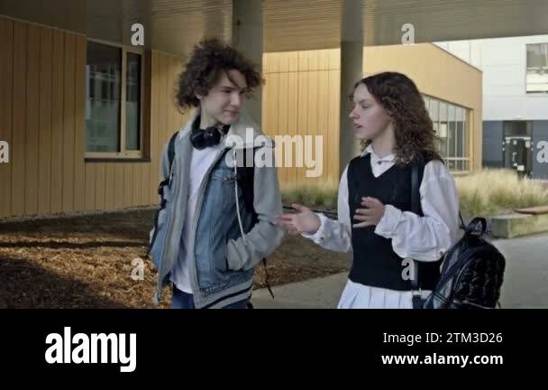 Two cute high school students, a guy and a girl, are walking around the ...