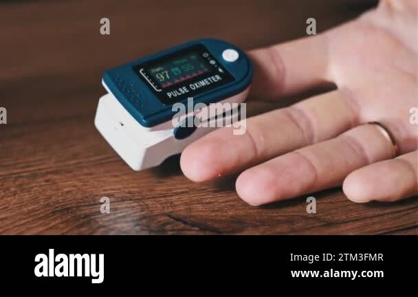 Man measures pulse and oxygen saturation with a pulse oximeter at home ...