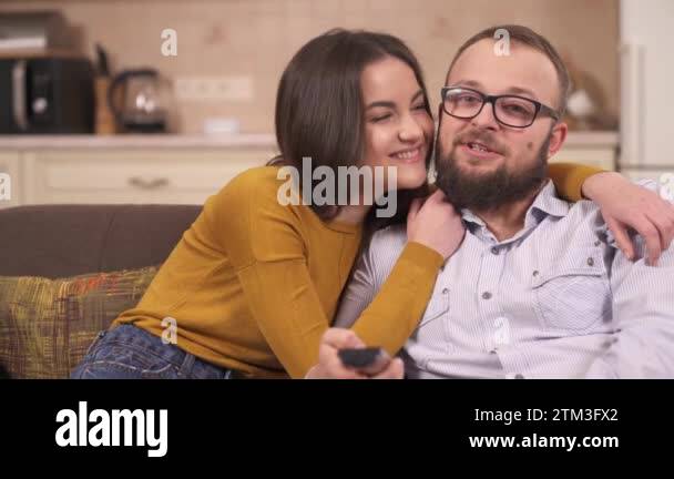 A pretty brunette and a bearded man in glasses sitting on the corner ...