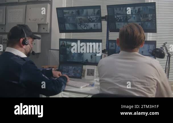 Security officers sit in observation room and monitor CCTV cameras with ...