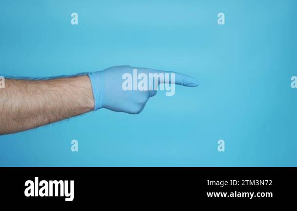 Body language pointing finger in a medical glove on a blue background ...