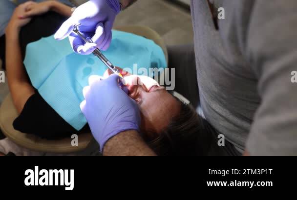 Dentist injecting woman with painkillers during wisdom tooth extraction ...