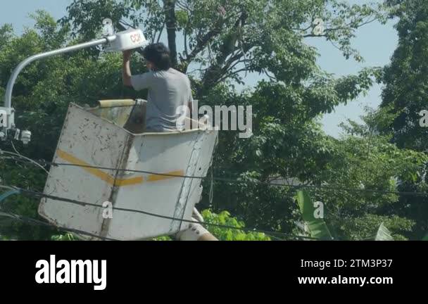Worker on height lifting platform installing new street light bulb ...