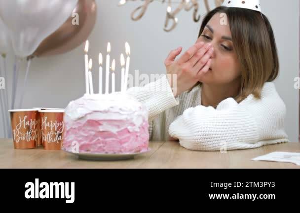 Sad birthday. Beautiful girl sits alone in front of a birthday cake and ...