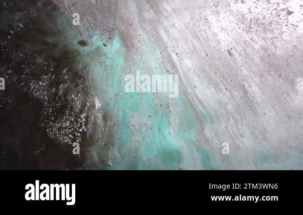 Turquoise pure color of ice inside the ice cave. Stones and icicles are ...