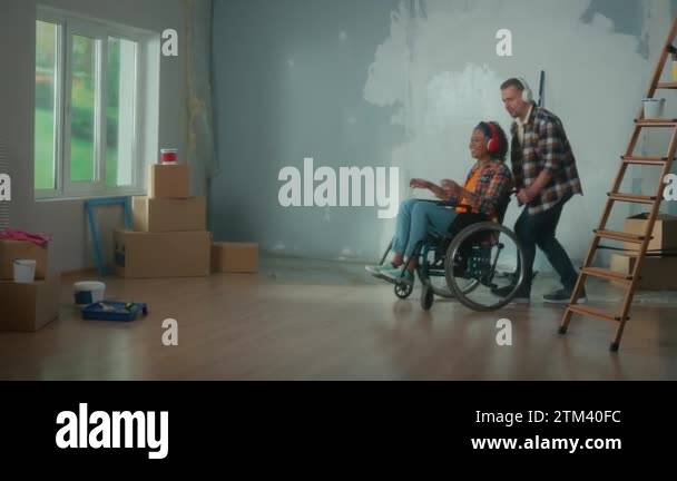 A white man wheeling an African American woman in a wheelchair into the ...