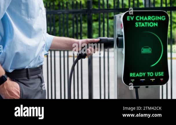 Businessman pull out EV charger from charging station to recharge ...