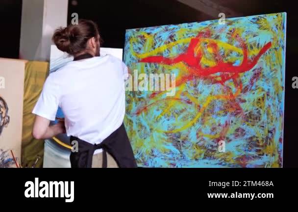 Charismatic talented beautiful artist approaches his canvas and uses ...