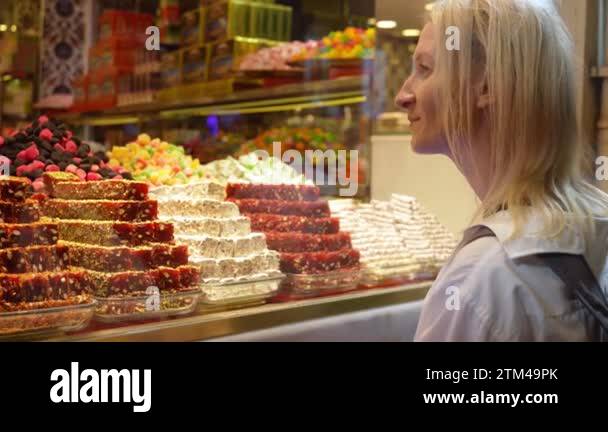Female tourist looking at turkish sweets through shop glass or window ...