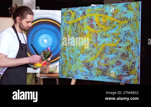 Focused talented artist working on abstract painting, using a brush to ...