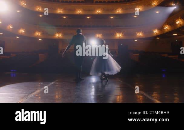 Pair of ballet dancers bow down in front of rows of seats. Ballerina ...